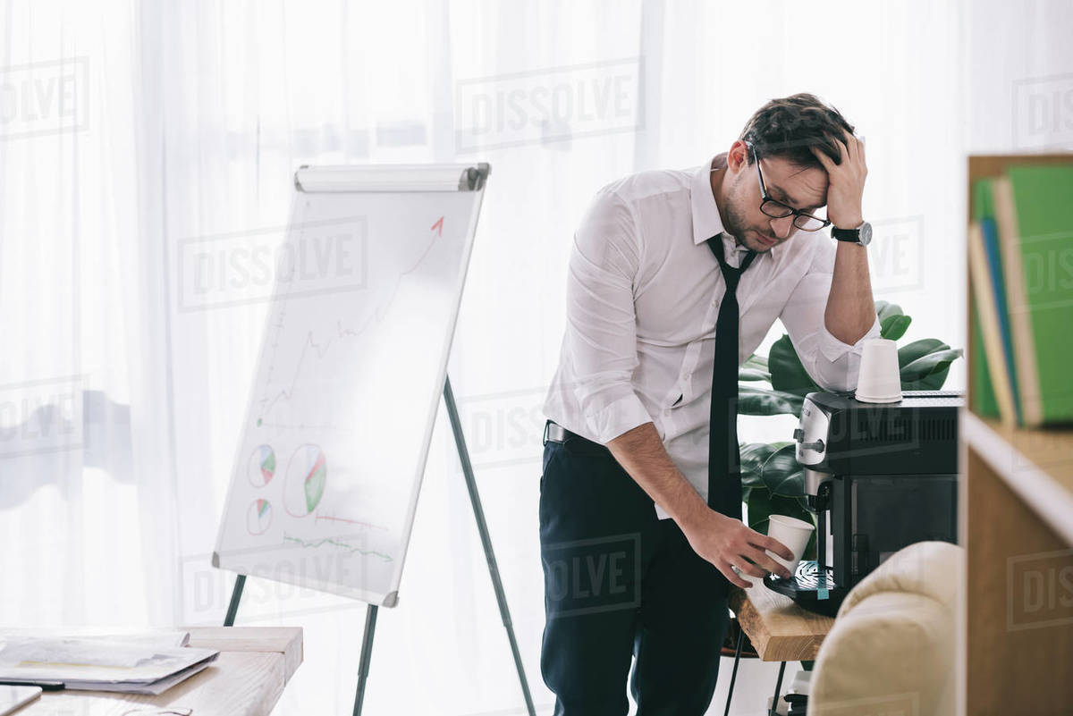 young overworked businessman pouring coffee from office machine ...