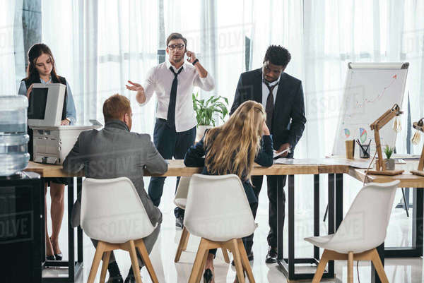 group of businesspeople having conversation at office while boss ...