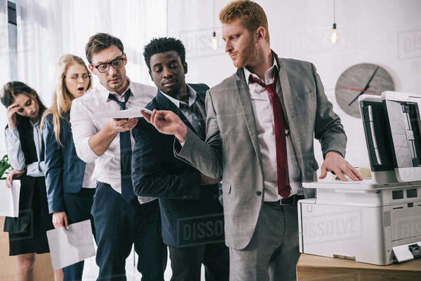 group of businesspeople standing in queue for copier at office ...