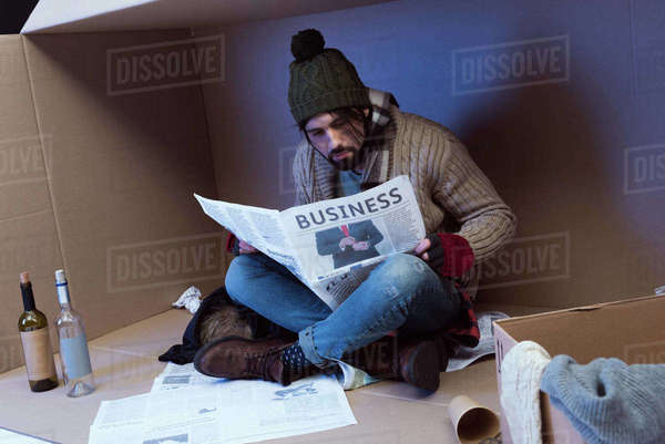 Homeless man reading business newspaper in cardboard box - Royalty-free ...