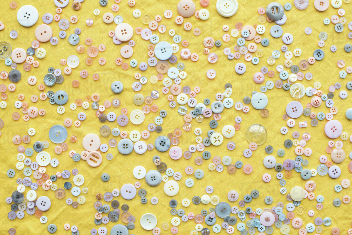 Top view of scattered colorful buttons on yellow cloth background ...