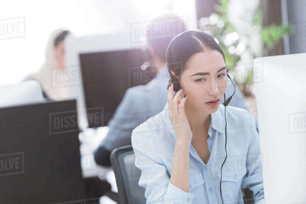 Selective focus of concentrated asian call center operator in headset ...
