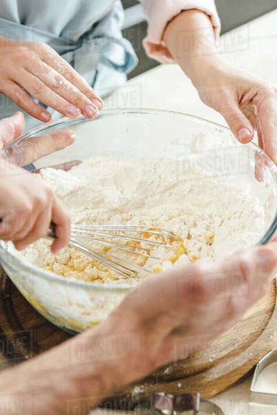 Cropped image of family hands mixing dough together in bowl - Royalty ...