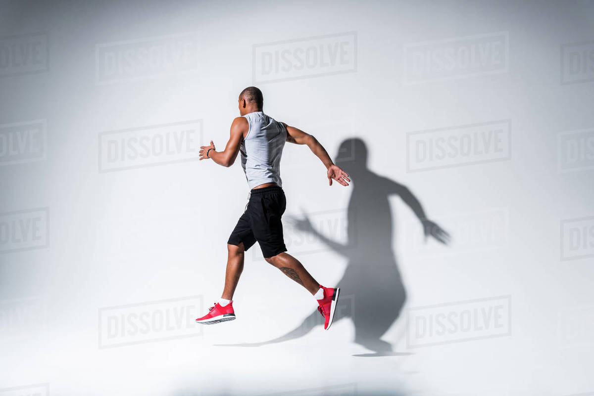 Full length view of young african american sportsman running on grey ...