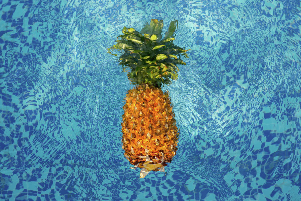 Pineapple floating in blue water of swimming pool - Royalty-free Stock ...
