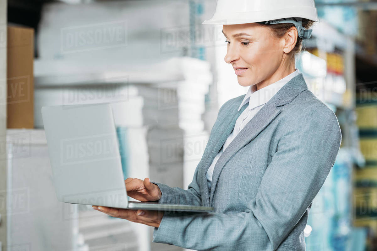 Female inspector in helmet with laptop in warehouse - Royalty-free ...