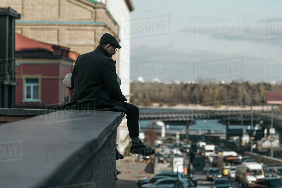 Stylish middle aged man sitting on roof of building - Royalty-free ...