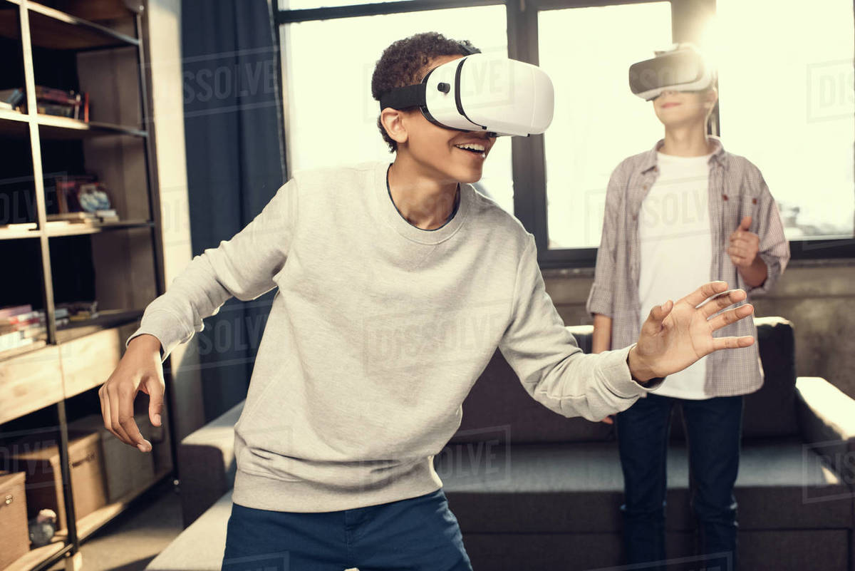 Teenage boys wearing virtual reality headsets at home, teenagers ...