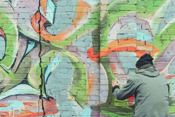 Back view of man painting colorful graffiti on wall - Stock Photo ...