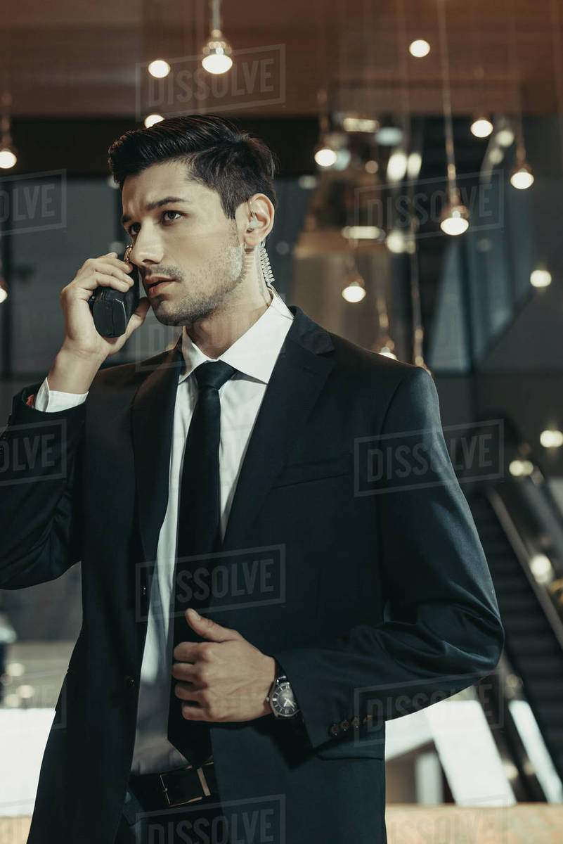 Handsome security guard talking by portable radio in business center ...