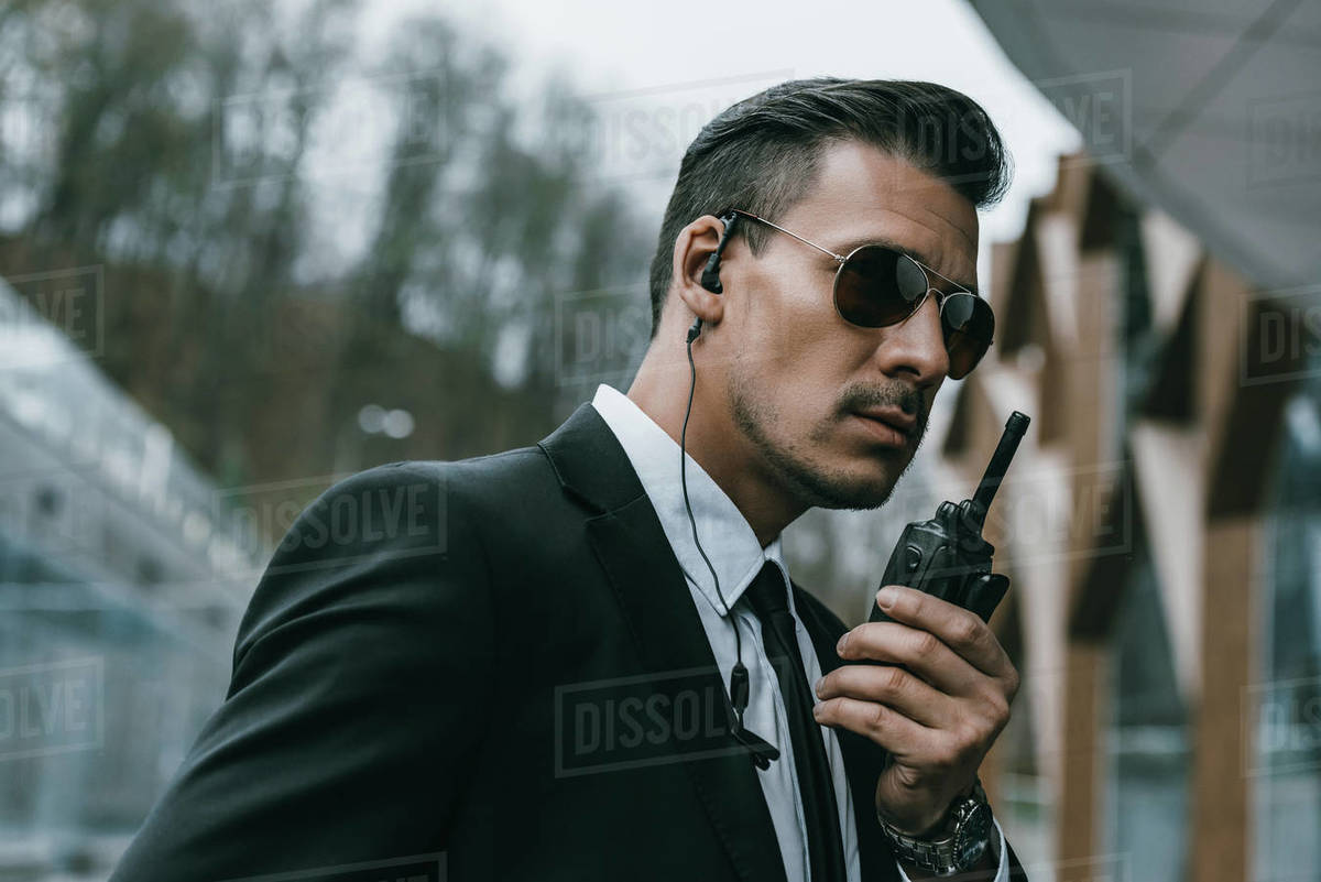 Serious handsome security guard talking by portable radio - Royalty ...