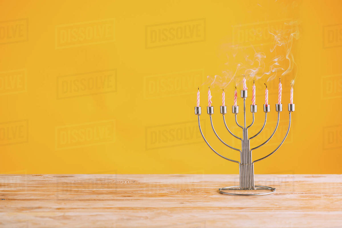 Menorah with candles standing on wooden tabletop on yellow, hanukkah ...