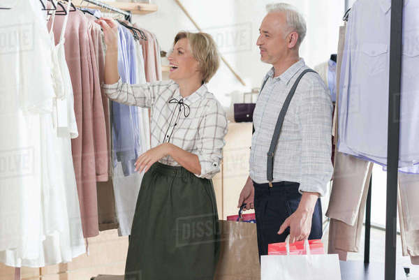 Woman and man laughing near clothes rack in a store - Stock Photo ...