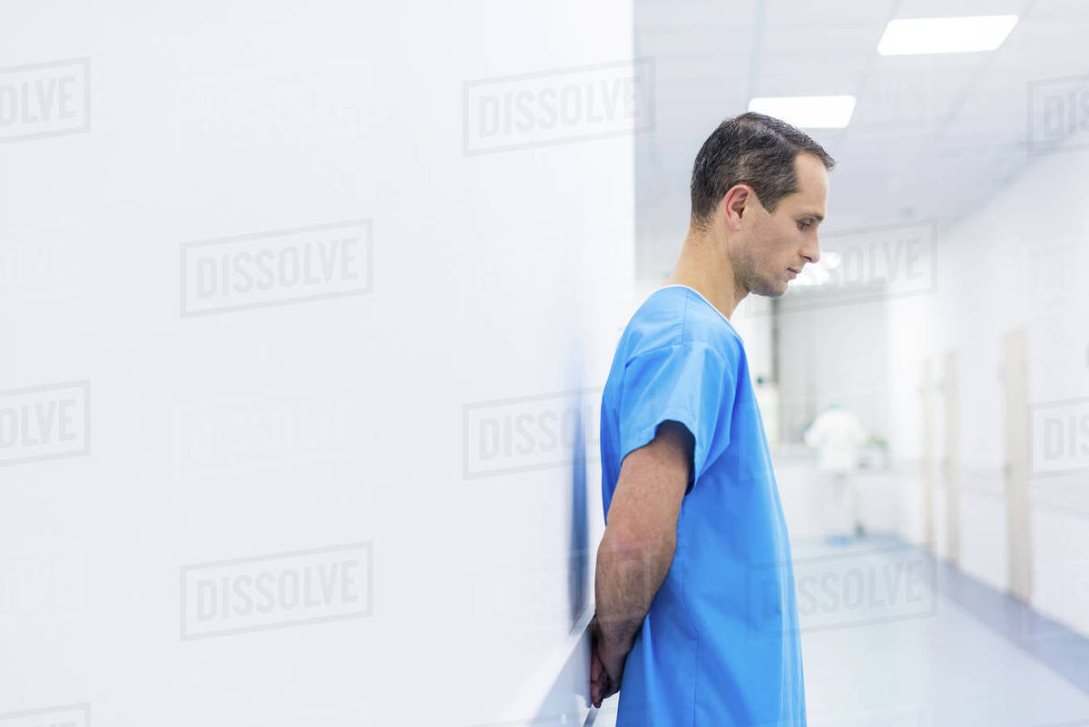 upset male patient in medical gown standing in hospital - Stock Photo ...