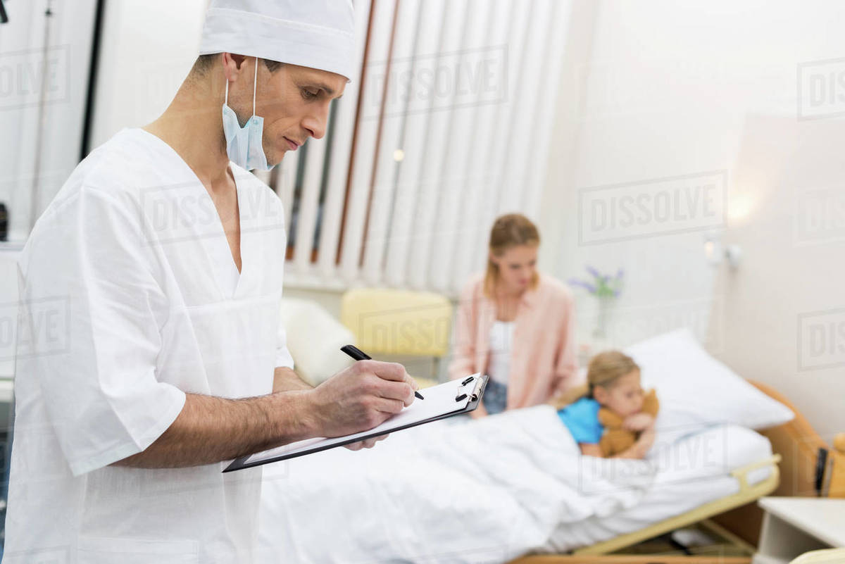 doctor writing something to clipboard in hospital - Stock Photo - Dissolve