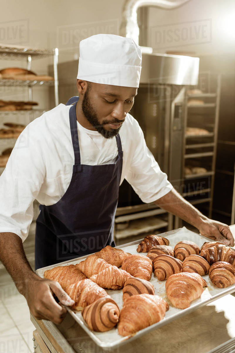 Baker holding tray with croissants on baking manufacture - Stock Photo ...