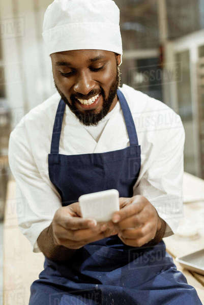 Young african american baker with hands covered in flour using ...