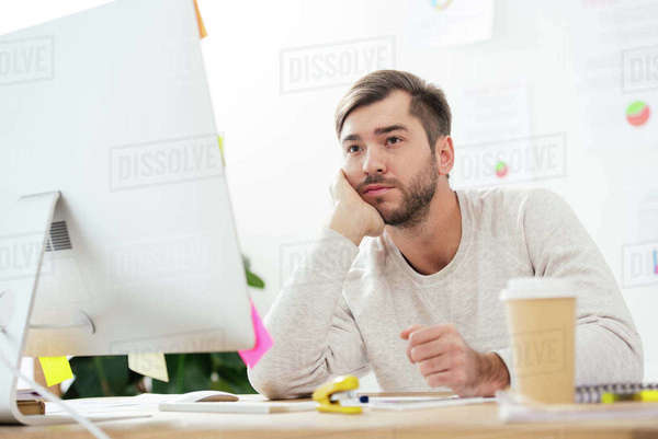 Bored marketing manager looking at computer screen at workplace in ...