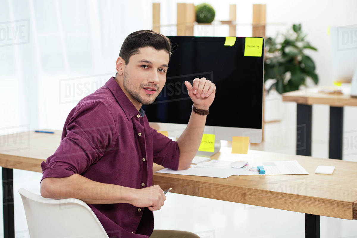 Young marketing manager looking at camera at workplace with blank ...