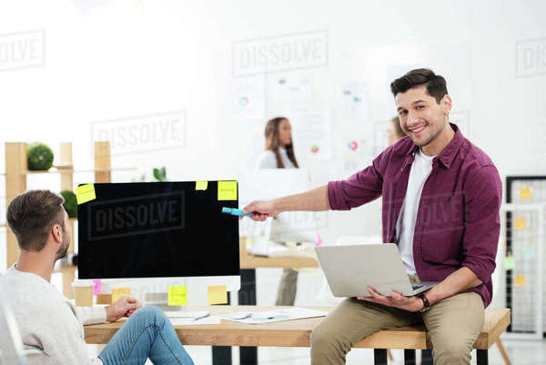 Businessman pointing at blank computer screen while working at ...