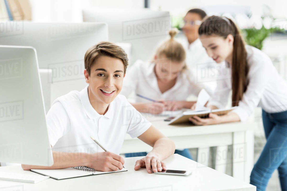 Portrait of smiling student looking at camera while sitting at table ...