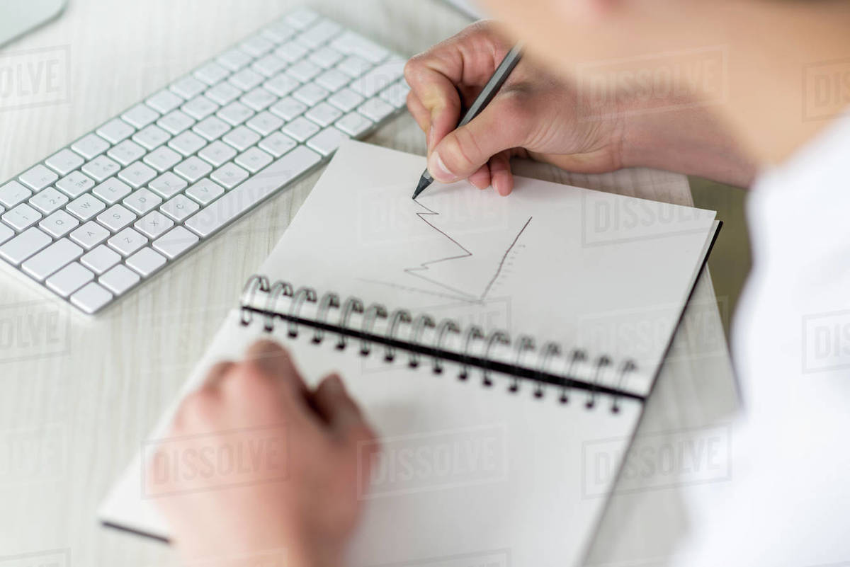 Partial view of student drawing graphic in notebook while doing ...
