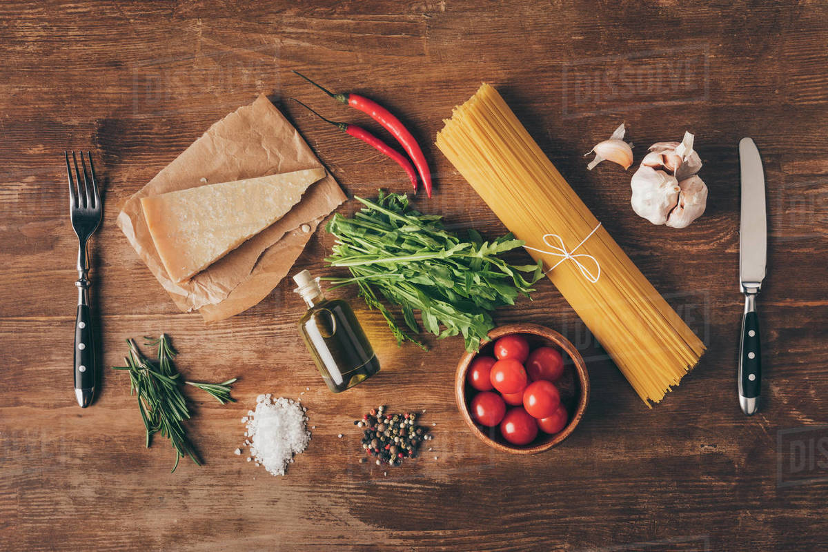 Top view of row pasta, fresh ingredients, Parmesan, fork and knife on ...