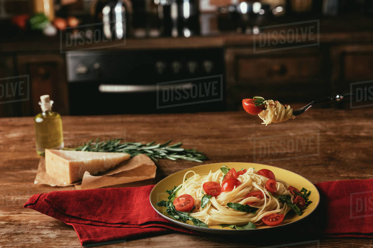 Delicious italian pasta with tomatoes and arugula in plate on table ...