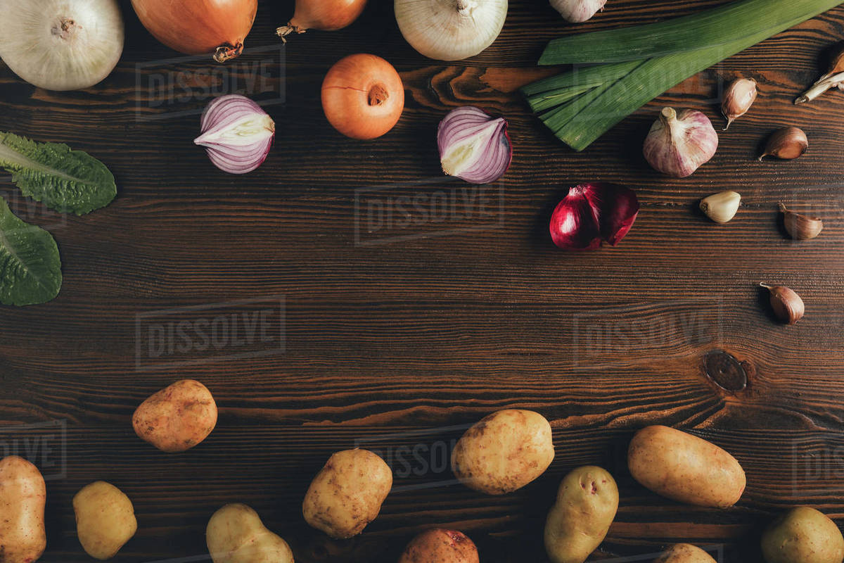 Top view of potatoes, onion and garlic on a table - Stock Photo - Dissolve