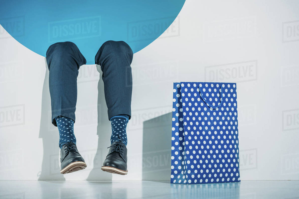 Partial view of stylish young man with shopping bag falling into hole ...