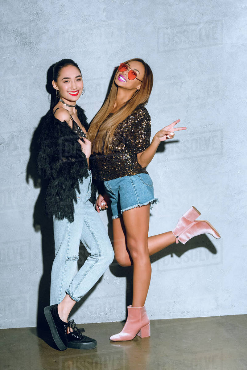 Full length view of beautiful fashionable multiethnic girls smiling at ...