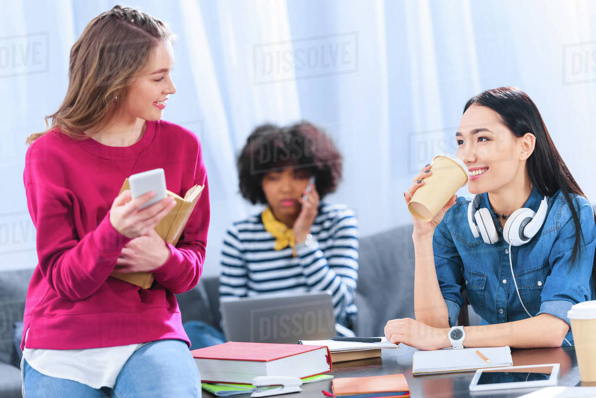 Selective focus of smiling multiracial young students studying together ...
