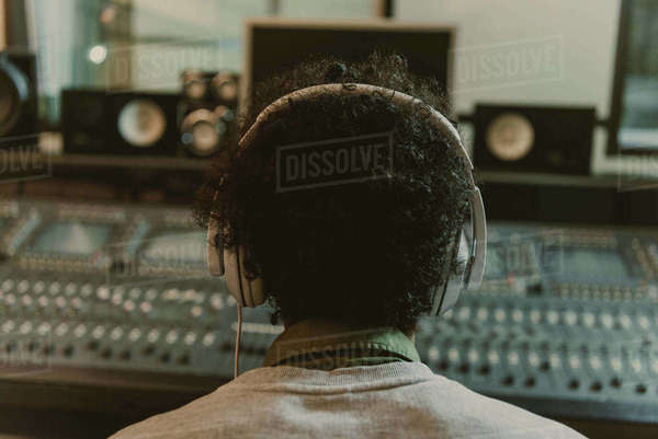 back view of sound producer in headphones sitting at studio - Royalty ...