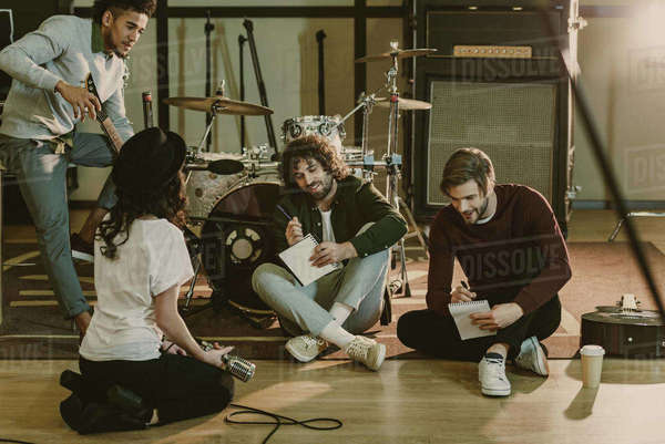 young music band sitting on floor and creating text for song together ...