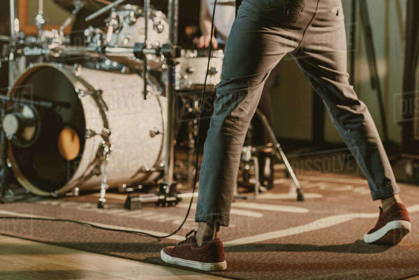 cropped shot of musician standing in front of drum set on concert ...