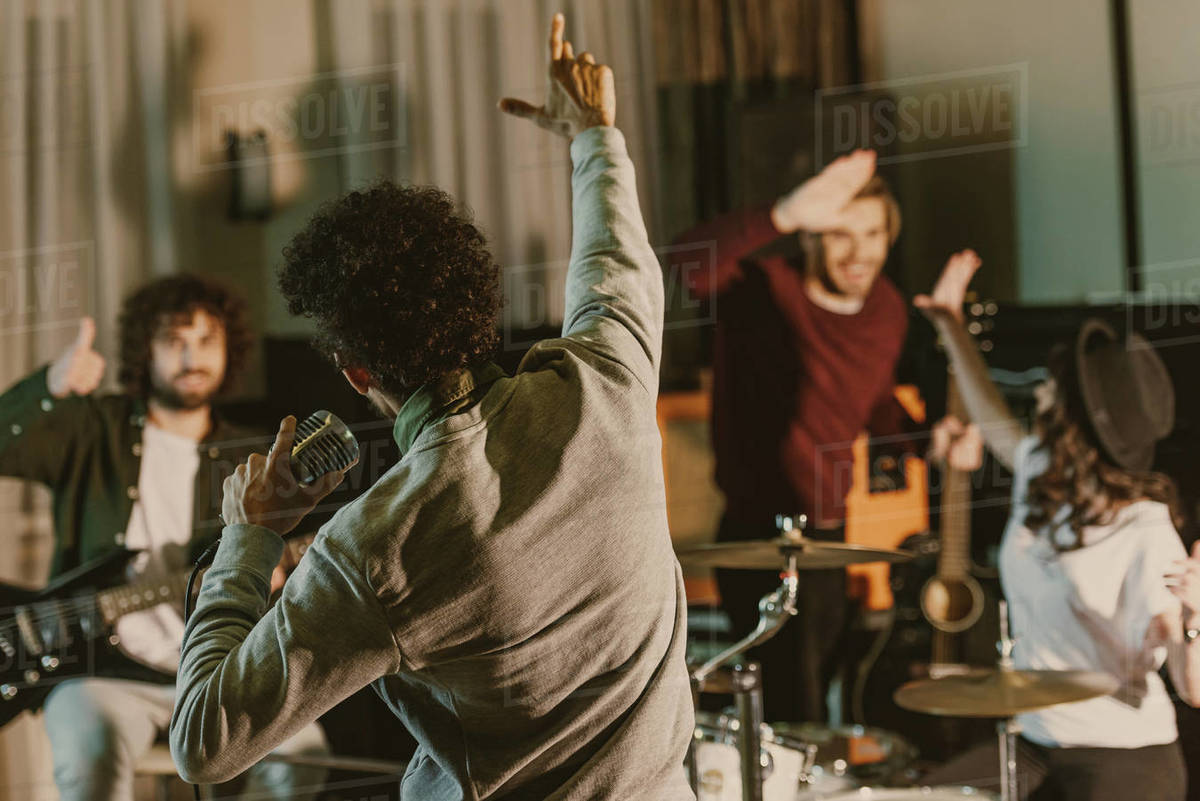singer stretching hand to happy music band while they having repetition ...