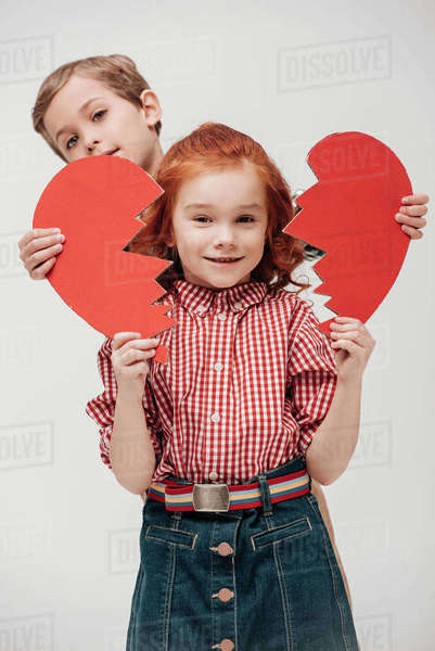 little boy holding parts of broken heart and adorable little girl ...