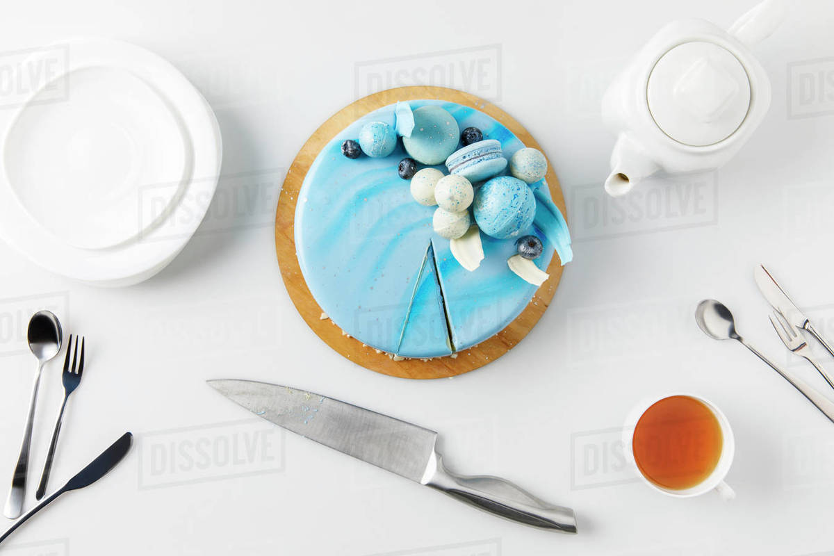 Top view of cake on chopping board with knife, plates and tea isolated ...