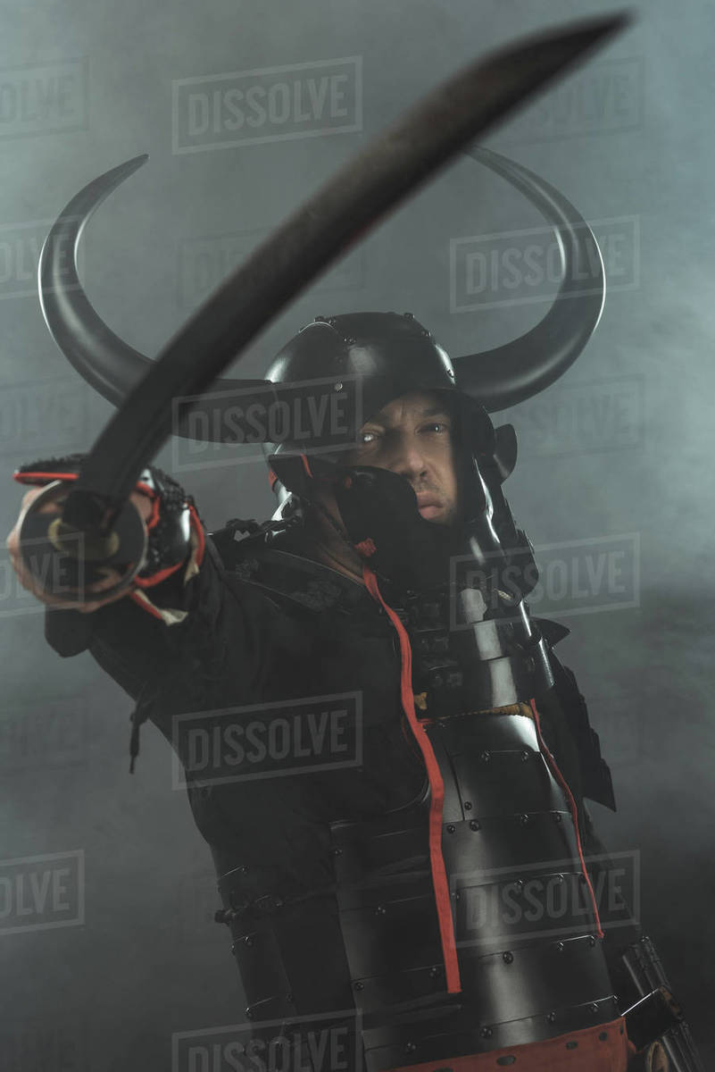 Close-up shot of samurai in traditional armor with katana sword on dark ...