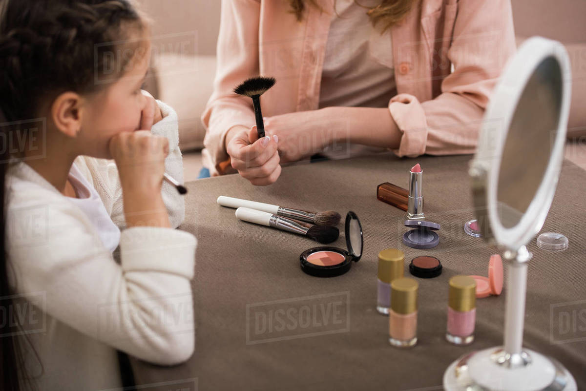 Cropped shot of mother and adorable little daughter applying makeup at ...