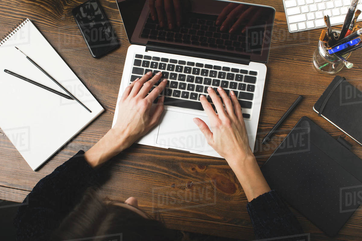 Top view of designer using laptop and working with graphics tablet ...