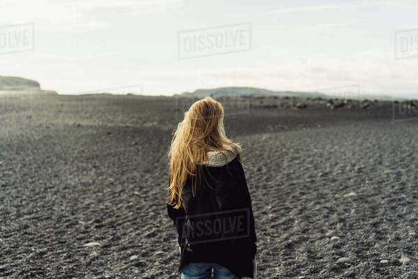 back view of young woman looking at beautiful wild icelandic landscape ...