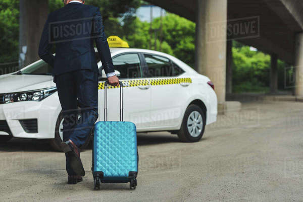 Back view of young man with suitcase running to taxi cab - Royalty-free ...