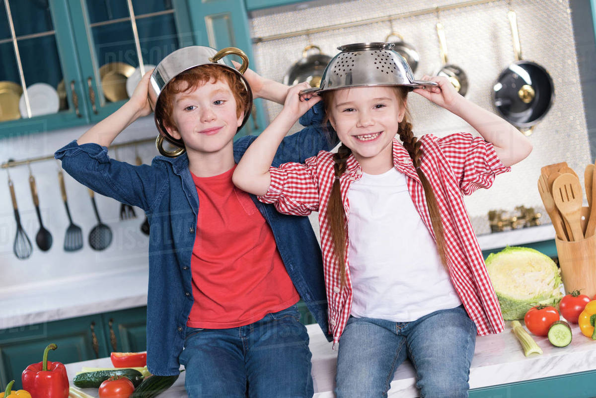 Adorable little kids with utensils on heads smiling at camera in ...