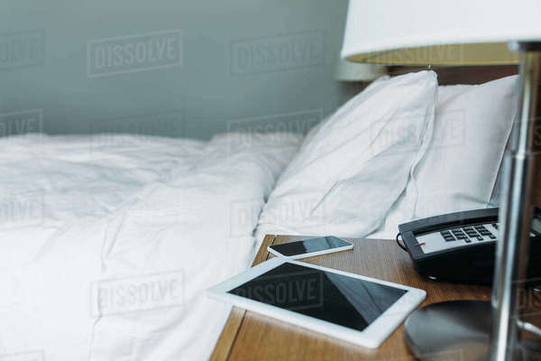 smartphone and tablet on bedside table in hotel room - Royalty-free ...