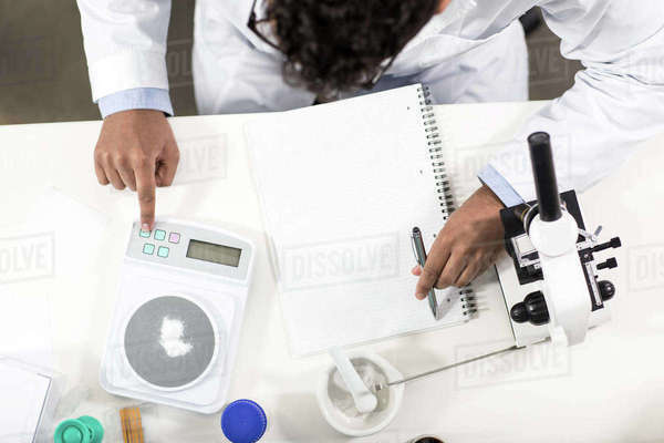 Overhead view of young scientist working with electronic scales and ...