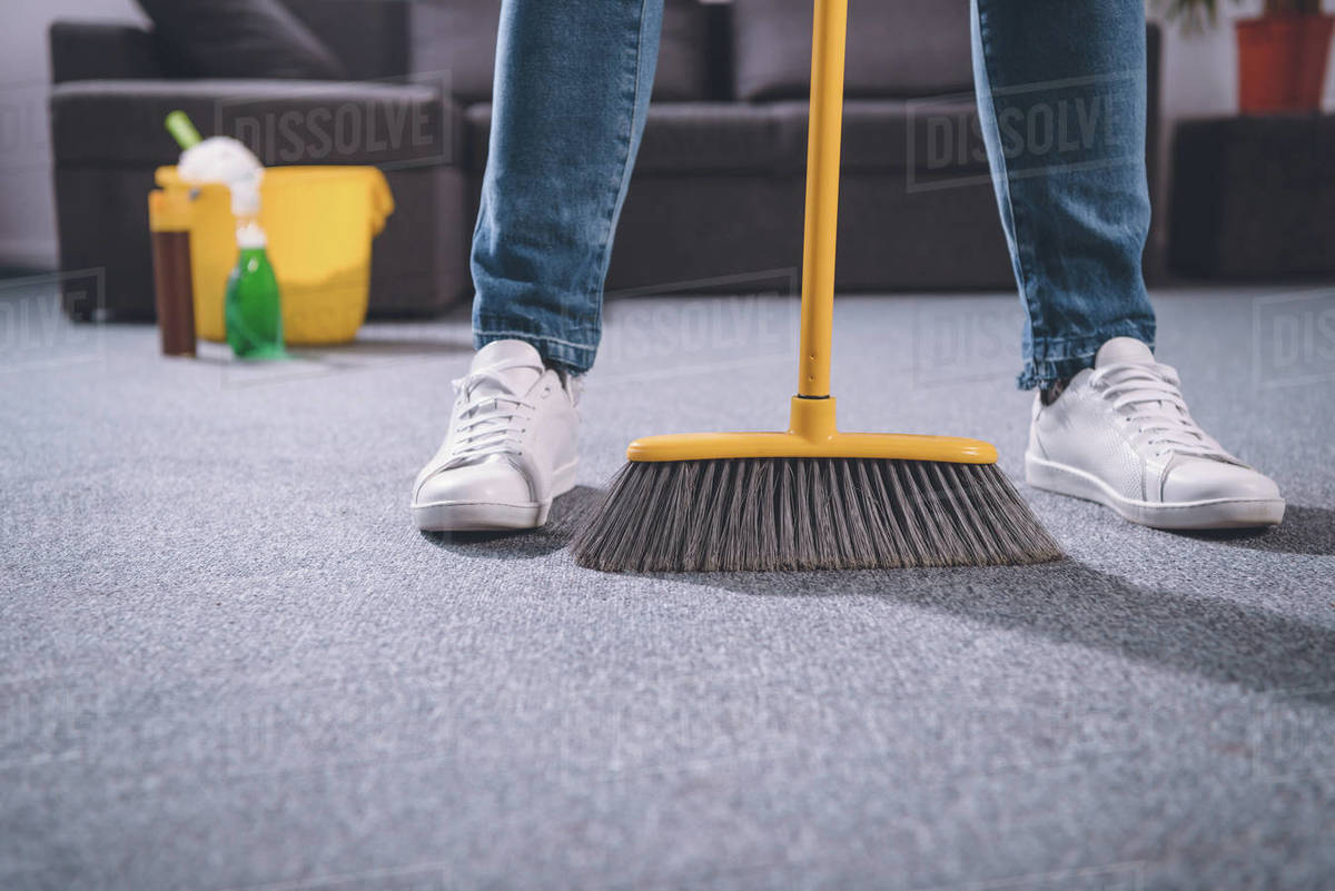 Cropped image of man standing with broom in living room - Royalty-free ...