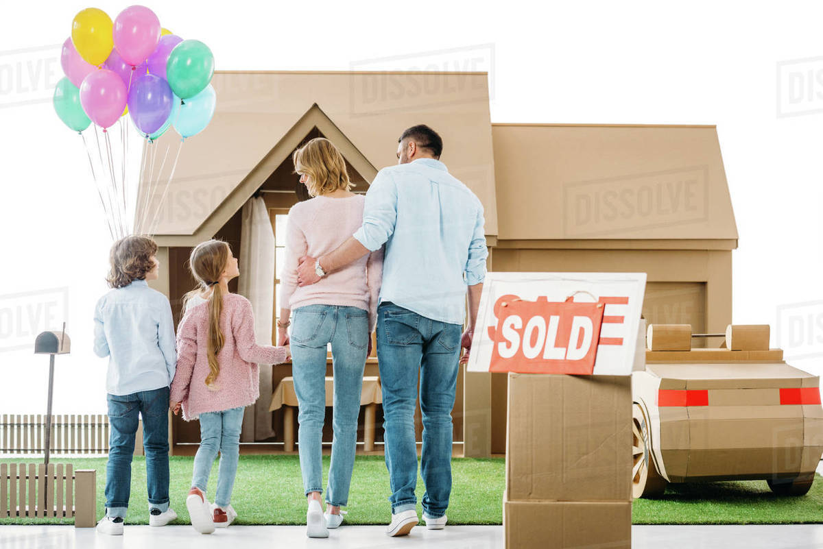 Back View Of Young Family Moving Into New Cardboard House Isolated On