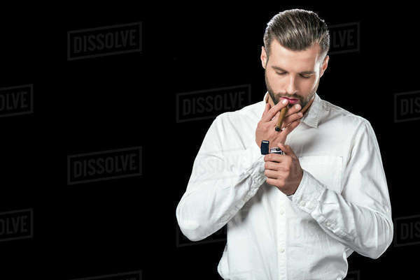 Handsome man lightning cigar with lighter, isolated on black - Royalty ...