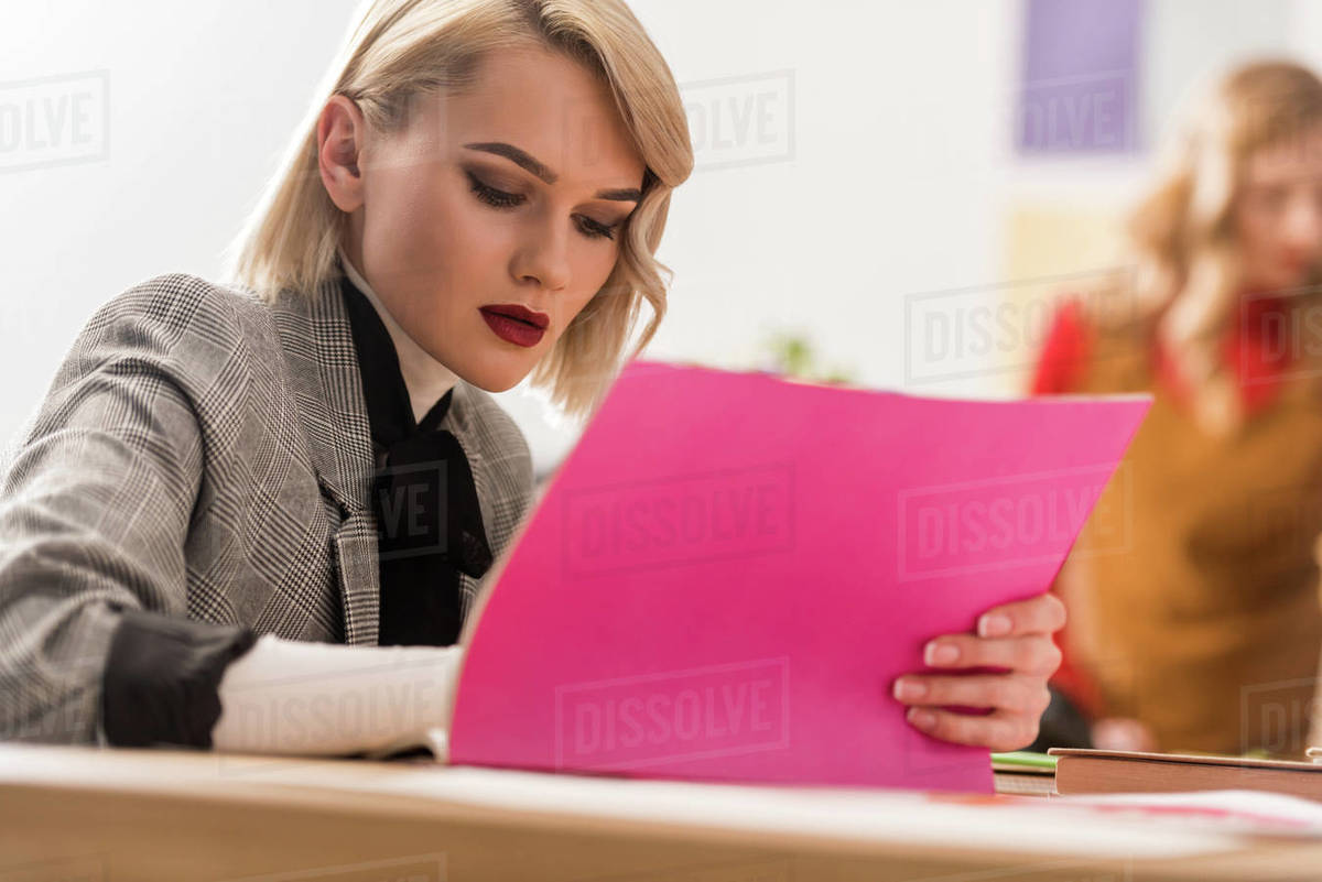 Attractive fashion magazine editor doing paperwork in modern office ...